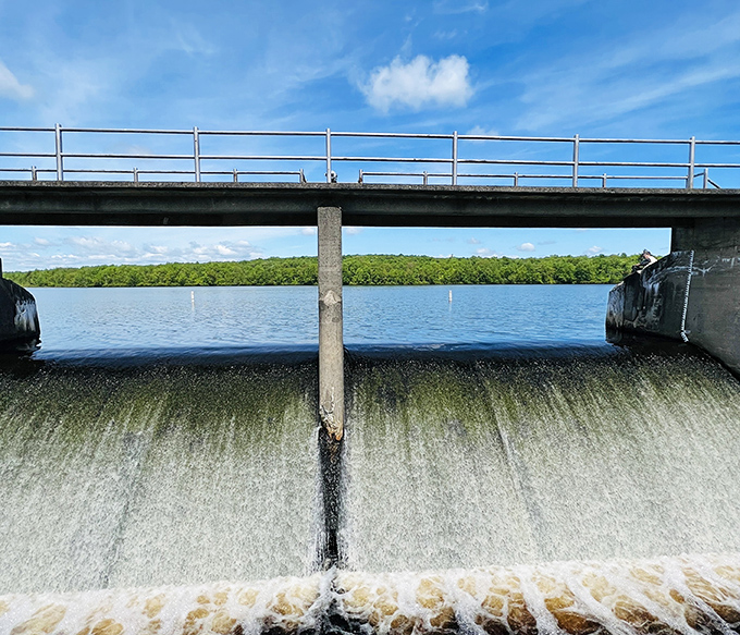 Water cascades dramatically over the dam, nature's version of a Pennsylvania power move. Engineering meets wilderness in perfect harmony.