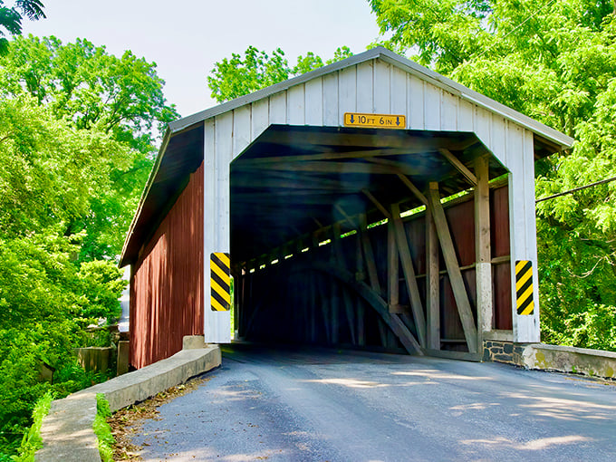 Summer transforms this historic structure into a postcard-perfect scene. The 10-foot clearance sign serves as both warning and invitation to enter another era.