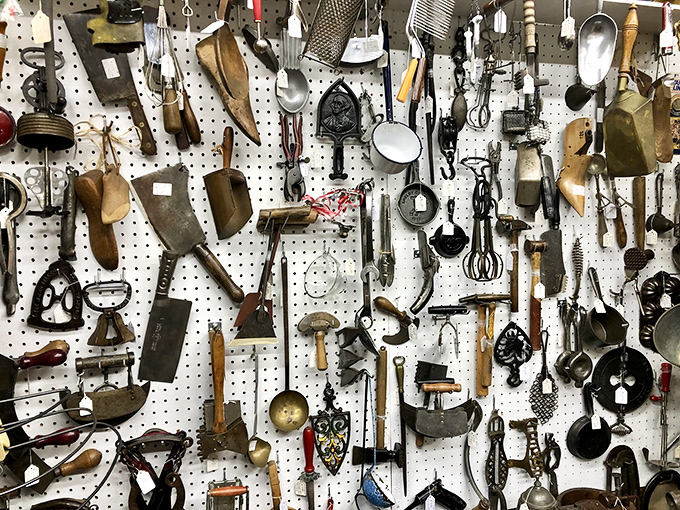 Kitchen implements with stories to tell. Each wooden handle and metal edge represents someone's daily life from decades past—practical poetry hanging on pegboard.