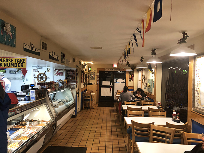 Nautical flags dance overhead while ship wheels stand sentinel on walls—this isn't just decoration, it's a promise of maritime delights to come.