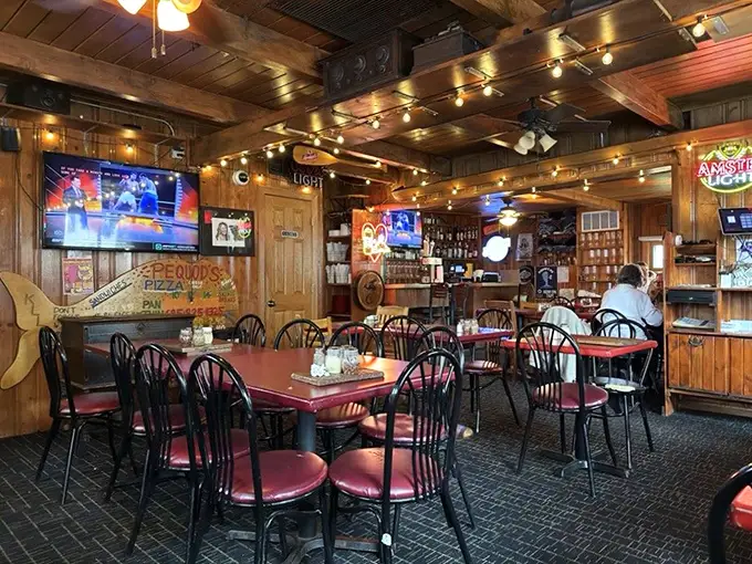 Wooden paneling, string lights, and red-cushioned chairs create that perfect "everybody knows your name" vibe. Comfort before the pizza storm.