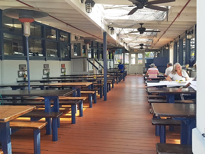 Nautical charm meets practical dining along this wooden walkway. The fishing nets overhead aren't just decoration—they're setting the perfect mood.