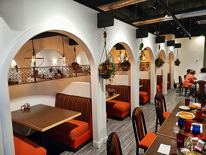 Step inside to discover cozy booth seating with vibrant orange cushions and charming archways that whisper "authentic comfort ahead."