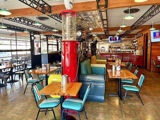 Retro meets rustic in this dining room where vintage gas pumps and motorcycles share space with turquoise chairs—a roadside Americana fever dream.