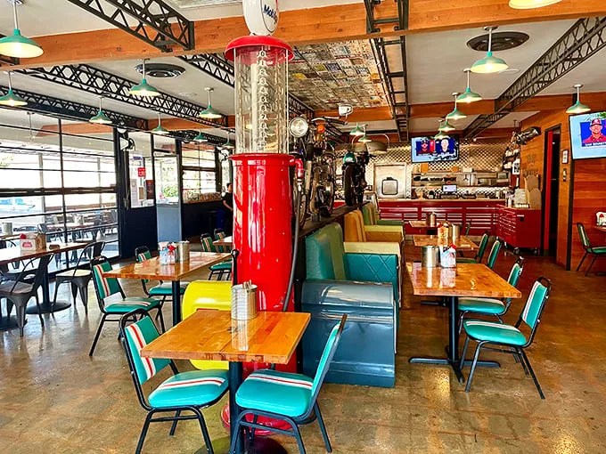 Retro meets rustic in this dining room where vintage gas pumps and motorcycles share space with turquoise chairs—a roadside Americana fever dream.