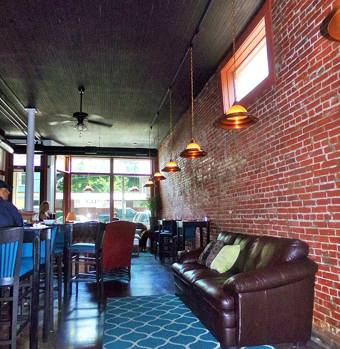 Exposed brick walls meet modern comfort inside Harbor Halcyon, where pendant lighting casts a warm glow over leather seating and a distinctive blue patterned floor.