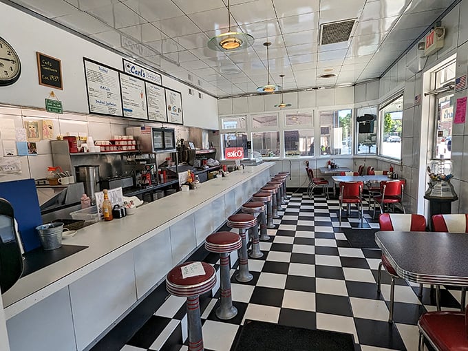 Classic Americana at its finest – a checkerboard floor, gleaming counter, and red vinyl stools where countless coffee cups have been refilled since Eisenhower was president.