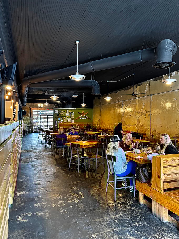 Industrial-chic meets cozy comfort inside, where gold-toned walls and exposed ductwork create the perfect backdrop for brunch-time conversations that flow as easily as the coffee.