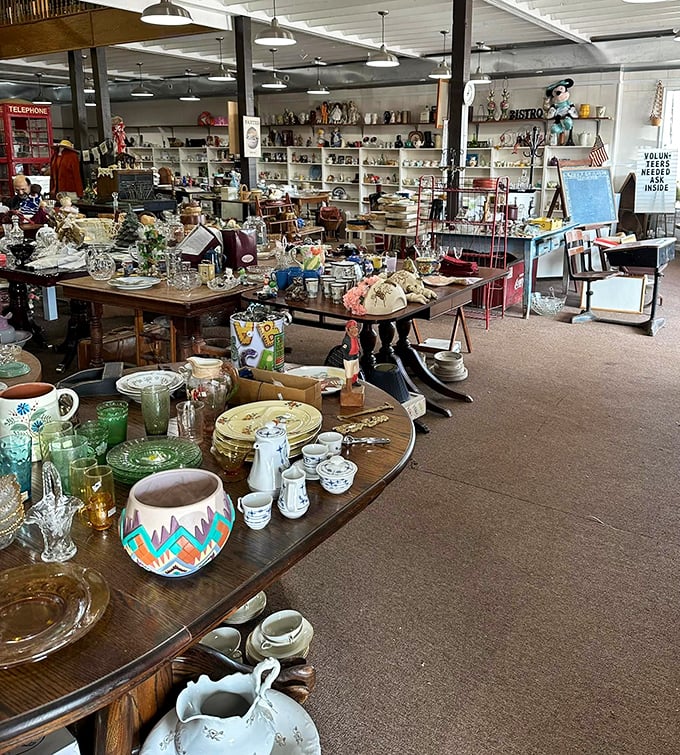 Tables overflow with vintage dishware and collectibles, creating an indoor archeological dig where every surface tells stories of dinners past.