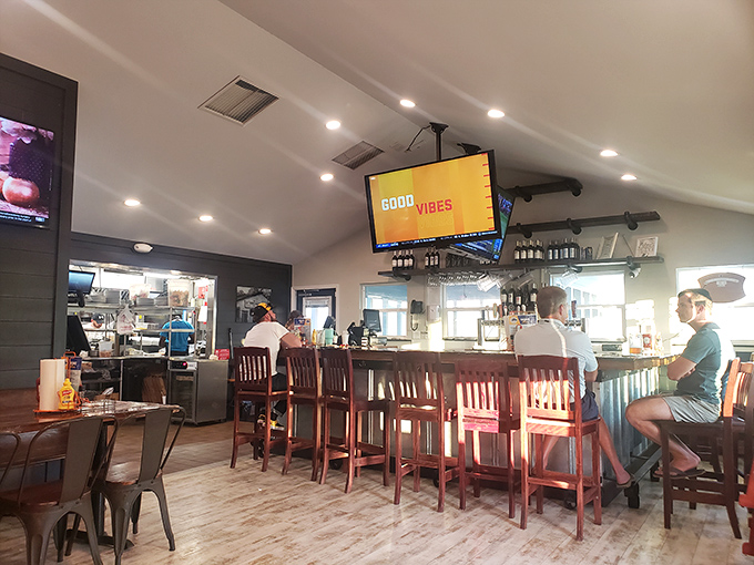 The "GOOD VIBES" sign isn't just decoration—it's truth in advertising. Wooden bar stools invite locals and visitors to settle in for coastal delights.
