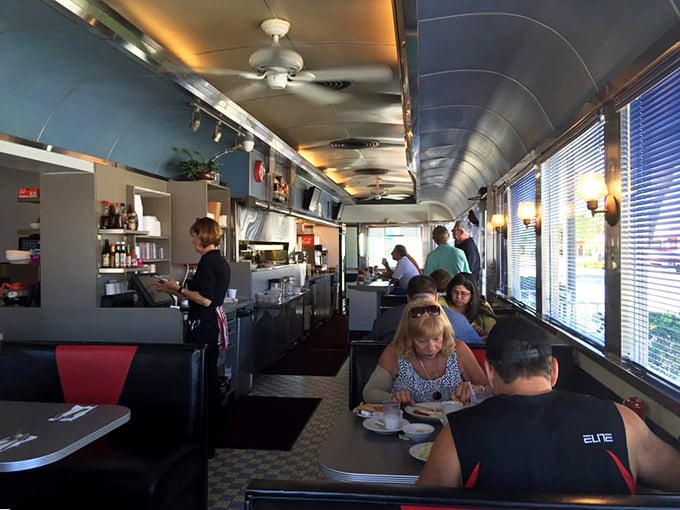 The classic railcar interior whispers stories of decades past while ceiling fans lazily spin overhead, keeping the atmosphere as cool as the vinyl booths.