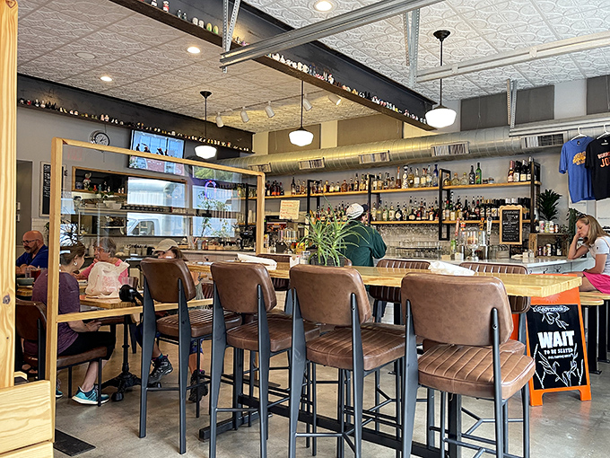 Inside, modern meets classic with leather bar chairs that practically whisper "stay awhile" beneath that gorgeous tin ceiling.