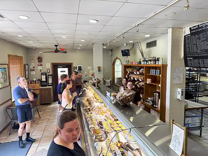 The moment of decision at the display case—where dreams are made and diets go to die. That pastry selection could make a cardiologist weep tears of both joy and professional concern.