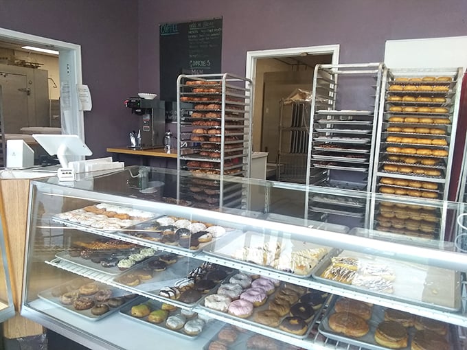 Donut heaven revealed: racks of freshly made treasures await their finishing touches while the display case tempts with an array of completed masterpieces.
