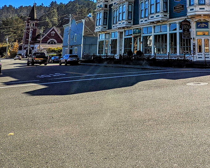 The Victorian Inn stands sentinel against forested hills, while a church steeple peeks through the skyline—quintessential Americana in architectural form.