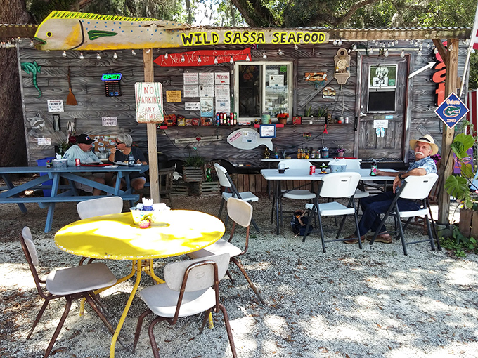 The humble outdoor seating area—complete with that unmissable sunshine-yellow table—might lack white tablecloths, but offers something pricier joints can't: genuine coastal atmosphere.