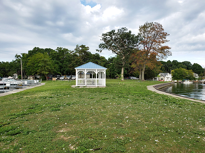 The quintessential gazebo moment awaits – where marriage proposals happen and ice cream cones drip while visitors contemplate life's bigger questions against a watery backdrop.