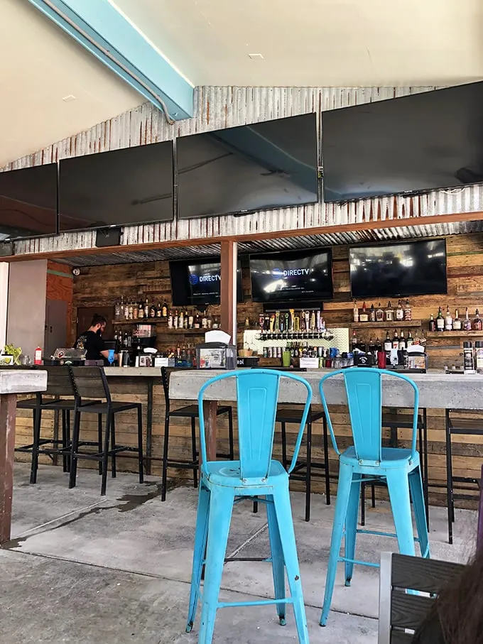 Rustic meets coastal at the bar, where turquoise chairs pop against weathered wood paneling—Florida's version of industrial chic.