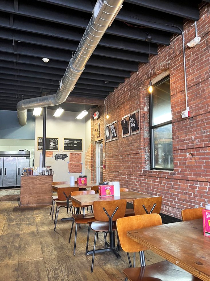 Industrial meets intimate in this no-frills dining space where exposed brick, wooden tables, and visible ductwork create the perfect backdrop for barbecue's starring role.