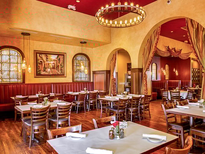 Step inside and you're transported to Tuscany—golden walls, burgundy accents, and that circular chandelier casting the kind of glow that makes everyone look like they're on vacation.