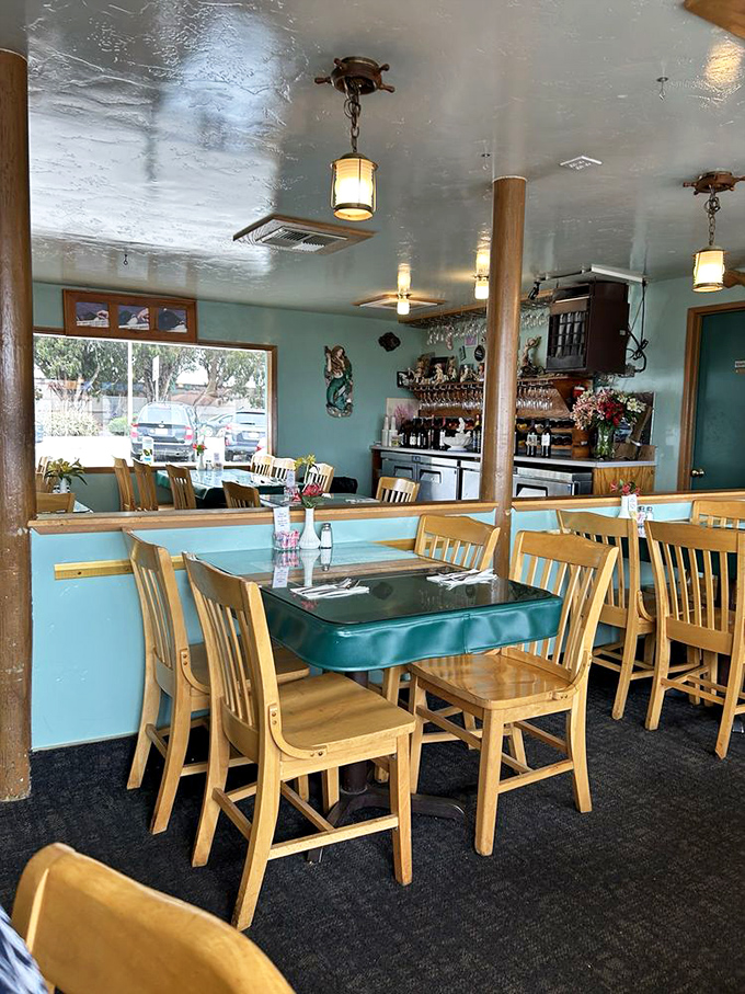 Aqua walls and wooden chairs create the perfect backdrop for seafood stories. This isn't designer chic—it's authentic coastal charm.