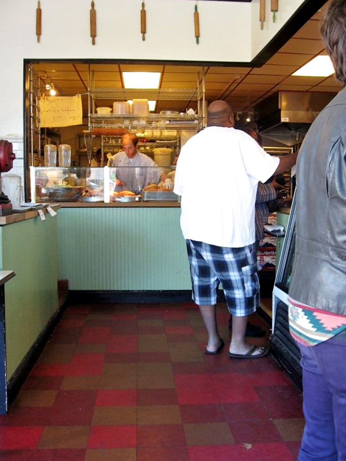 No fancy interior design consultants here—just a simple counter, checkerboard floor, and the promise of culinary magic happening behind the scenes.