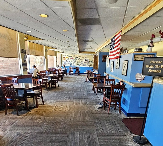 Step inside to a world where comfort reigns supreme – blue walls, wooden chairs, and an American flag that says, "Yes, we take breakfast seriously around here."