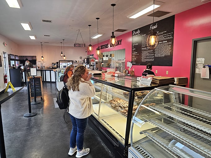 Step inside and the aroma hits you like a sugar-scented welcome committee. The pink accent wall and display cases showcase edible works of art.