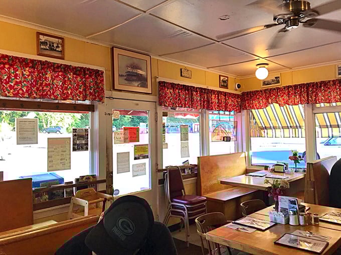 Cheerful red curtains and cozy wooden booths create that perfect small-town diner atmosphere where conversations flow as freely as the coffee.