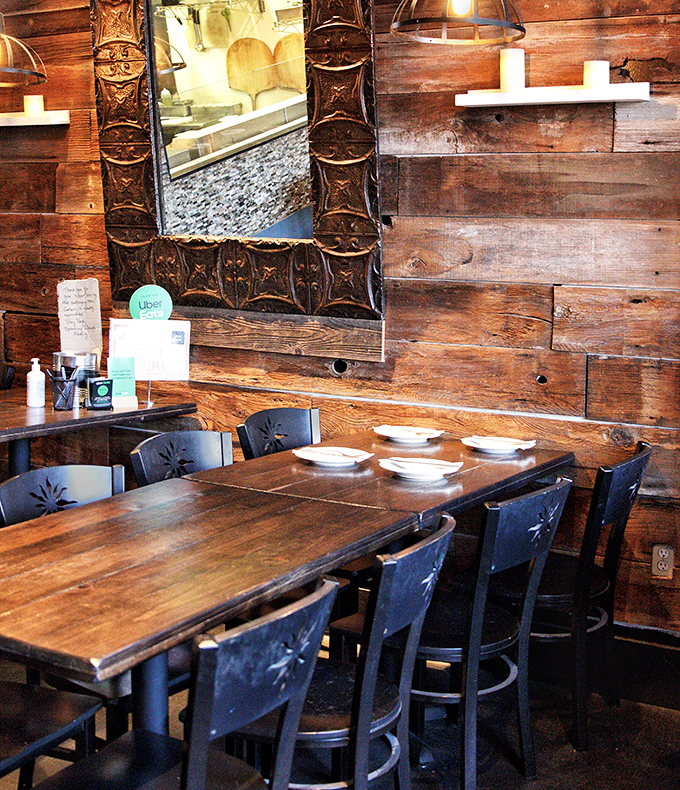 Reclaimed wood walls and ornate mirrors create that perfect "rustic chic" vibe—like your coolest friend's cabin suddenly started serving incredible pizza.