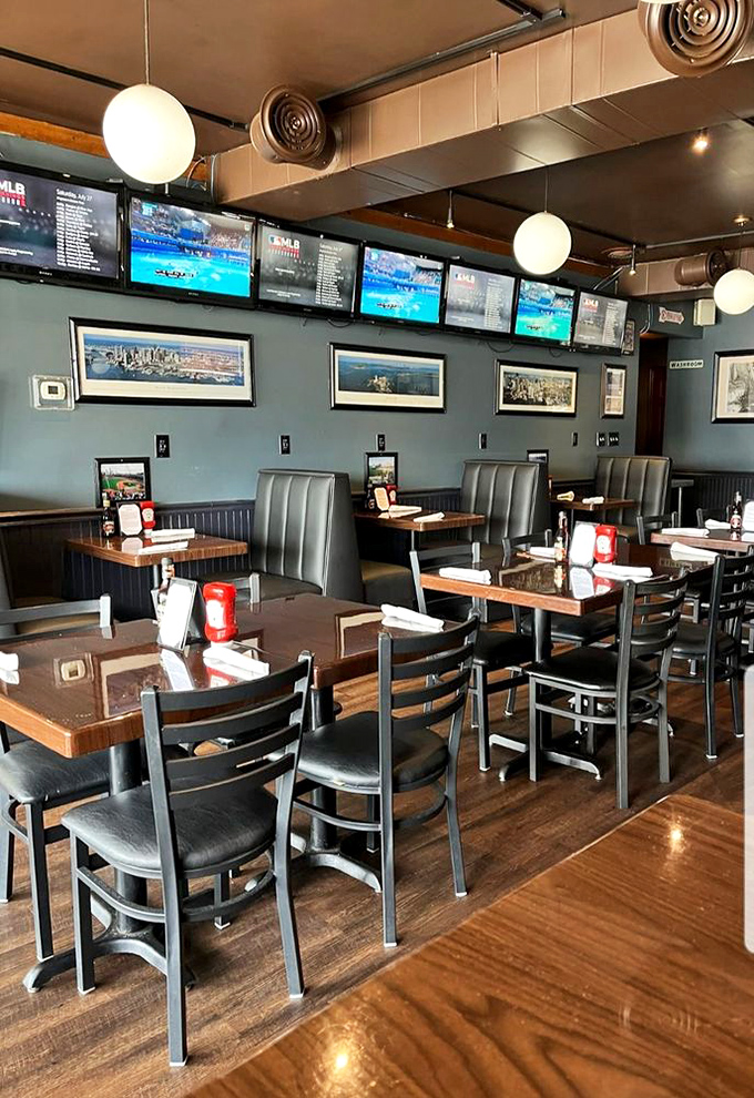 Inside, blue-gray walls and globe pendant lights create a cozy atmosphere where sports fans gather around TVs and wooden tables hold conversations as rich as the food.