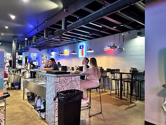 Inside, neon lights cast a warm glow over the industrial-chic space where barbecue pilgrims gather for their smoky salvation.