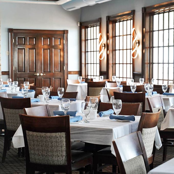 Crisp white tablecloths meet warm wood tones in this elegant dining room where the large windows frame the York River like living paintings.