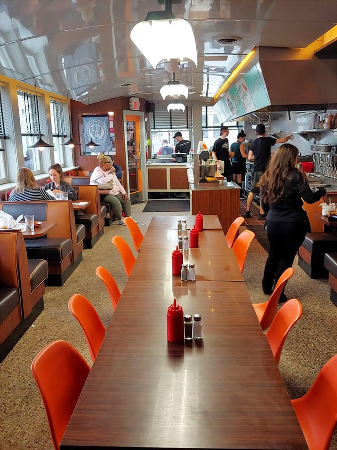 Inside, those orange chairs and wood-paneled booths aren't just seating—they're front-row tickets to the greatest show in comfort food.