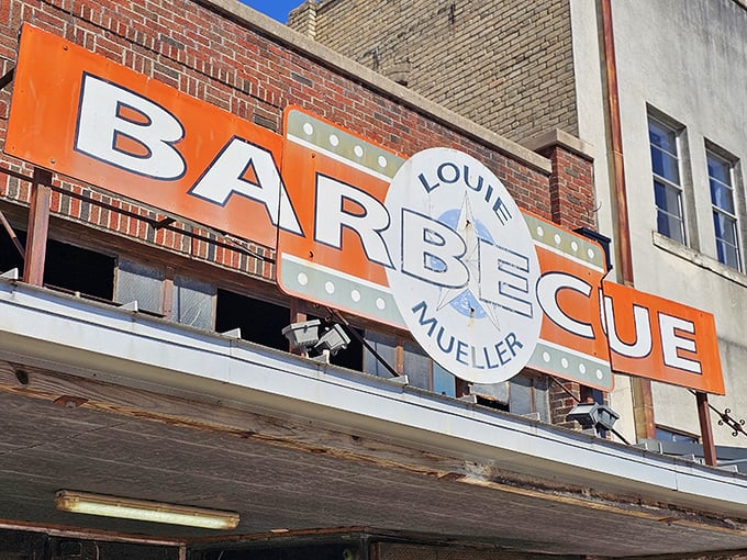 Louie Mueller's iconic sign glows like a barbecue beacon. This orange and white landmark has guided hungry pilgrims for generations.
