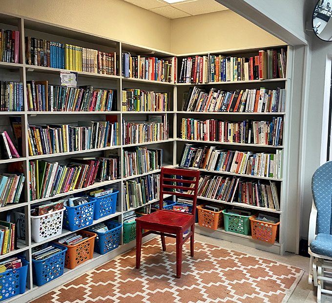 A bibliophile's dream corner where that red chair isn't just furniture—it's an invitation to lose yourself in someone else's story.
