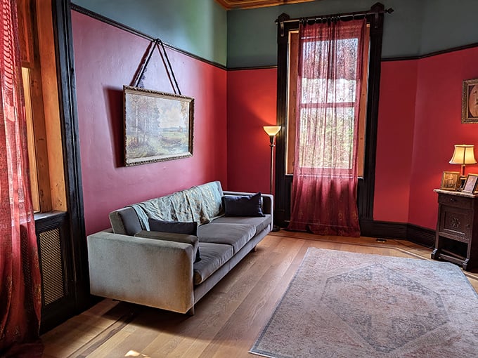 Bold crimson walls embrace this sitting room like a dramatic theater curtain, making even a casual conversation feel like the third act of a Gothic play.