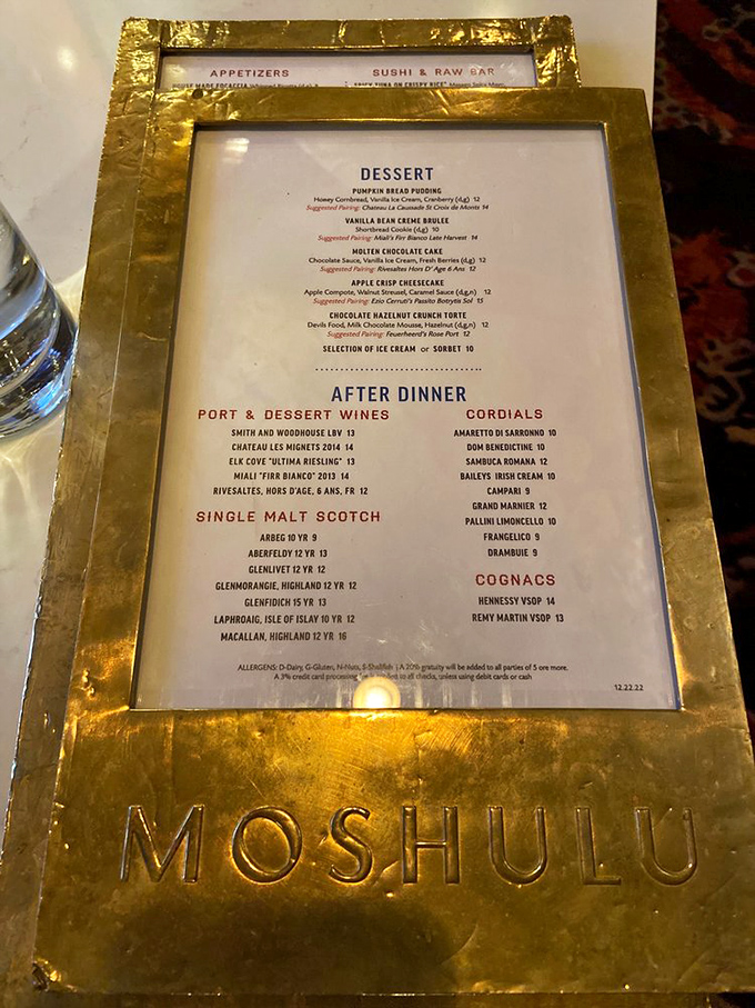 A dessert menu cradled in gold reminds you this isn't just any floating restaurant—it's maritime royalty serving pumpkin bread pudding and single malt scotches worthy of a captain's table.