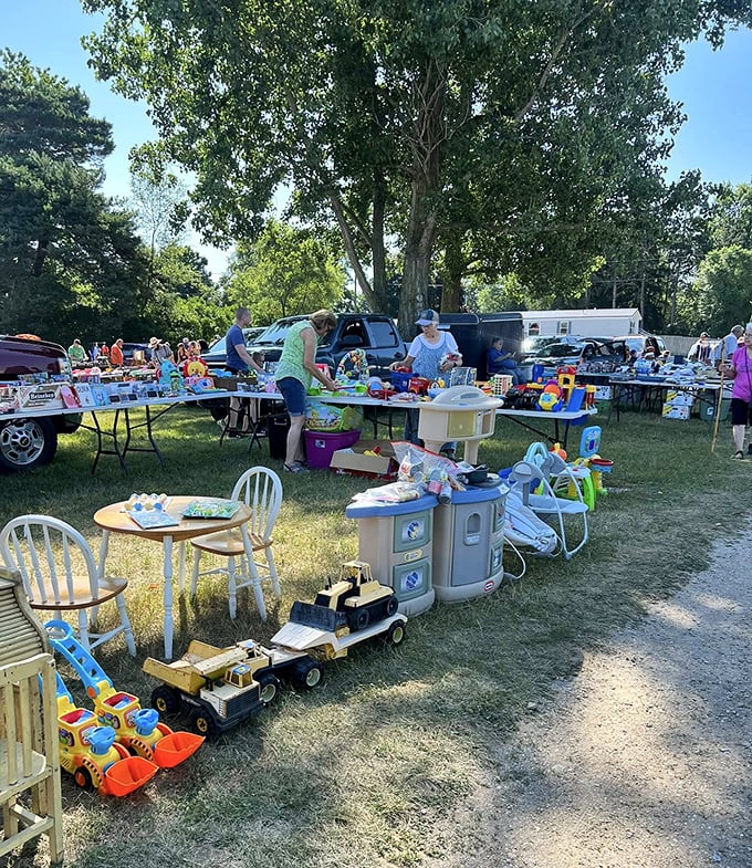 Childhood memories for sale! Colorful toys and kid-sized furniture await new homes while shoppers browse under the shade of towering Michigan trees.
