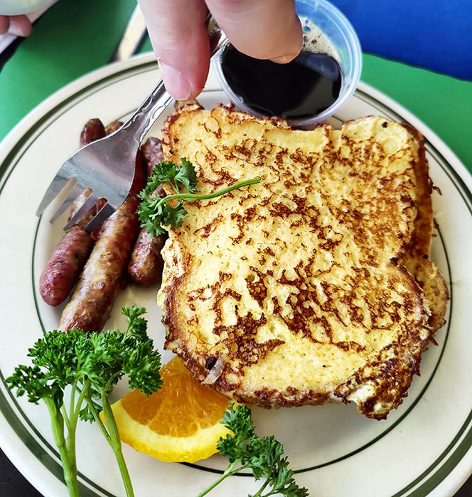 Golden-brown French toast that's been kissed by the griddle, served alongside sausage links that snap with each bite—breakfast perfection defined.