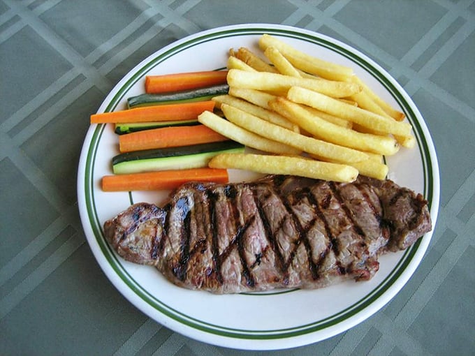 Behold the star of our show—the NY steak with perfect grill marks that whisper "I was cooked by someone who cares." Those fries and veggies aren't just sides, they're supporting actors deserving their own award.