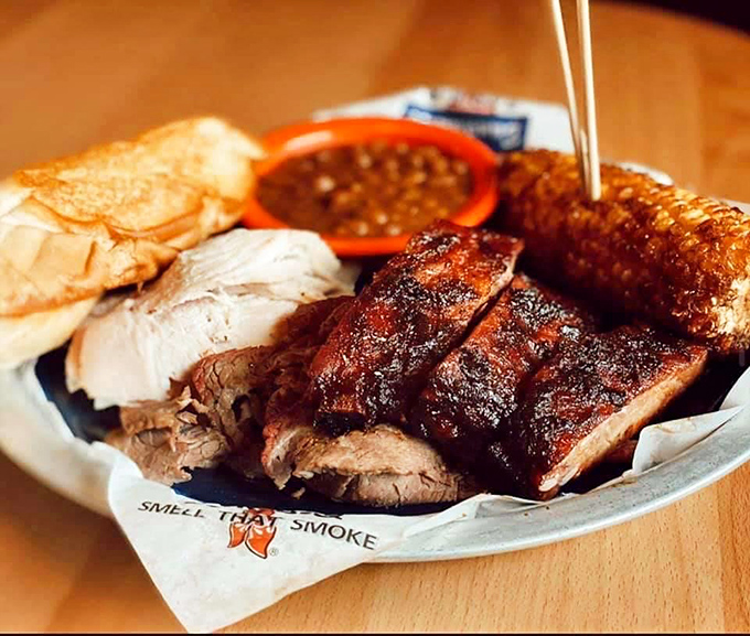 Behold the holy trinity of barbecue – perfectly sliced brisket, pulled pork, and ribs – served with the reverence they deserve on paper that proudly proclaims "SMELL THAT SMOKE."