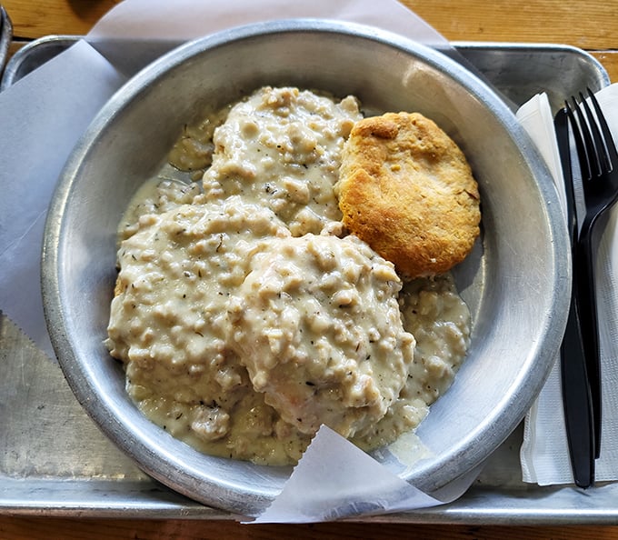 Behold the golden standard of biscuits and gravy – fluffy buttermilk perfection swimming in creamy, sausage-studded heaven.