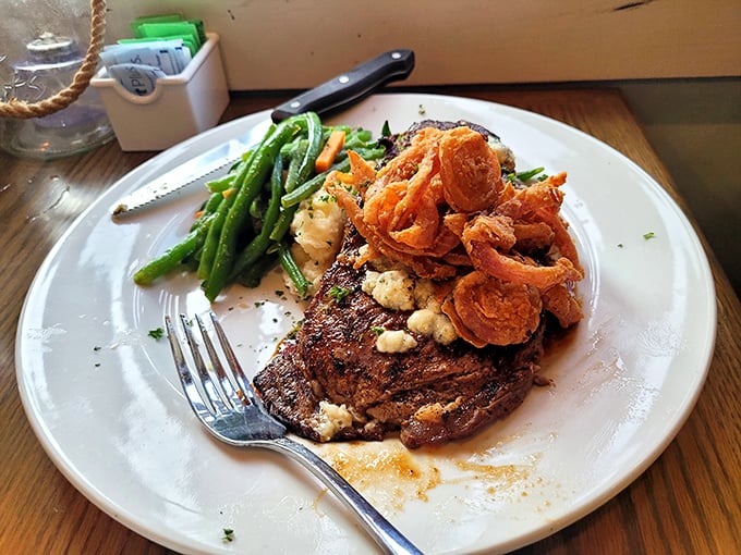 The legendary ribeye in all its glory—blue cheese crumbles melting into perfectly seared beef with crispy onions standing guard.