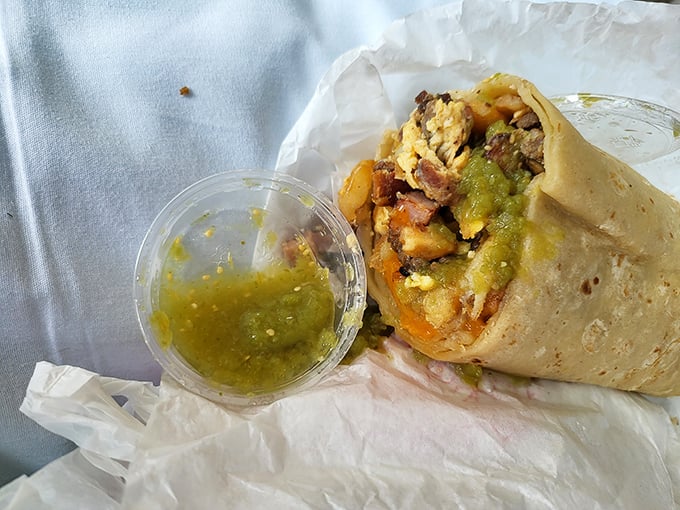 Behold the star of the show—eggs, potatoes, and meat wrapped in tortilla perfection, with salsa verde standing by for its supporting role.