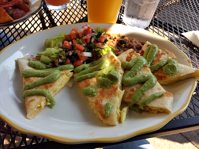 The breakfast quesadilla—where tortilla meets morning magic. Those green avocado drizzles aren't just garnish; they're little highways to flavor town.