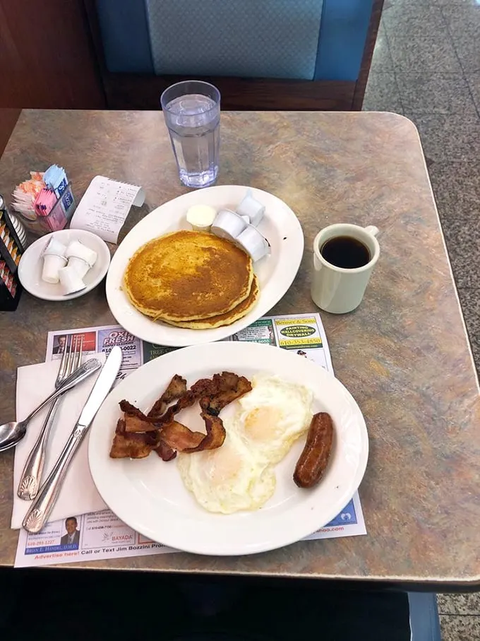 Breakfast perfection doesn't need fancy plating – just golden pancakes, perfectly cooked eggs, crispy bacon, and that iconic white coffee mug that somehow makes everything taste better.