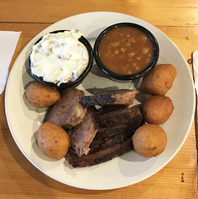 Brisket that doesn't just fall apart—it practically surrenders to your fork after its 12-hour smoke bath. Those hushpuppies aren't bad company either.
