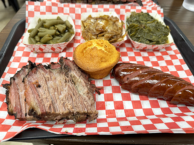 BBQ perfection on a red checkered canvas—brisket with that coveted smoke ring alongside sausage and sides that don't know the meaning of "afterthought."