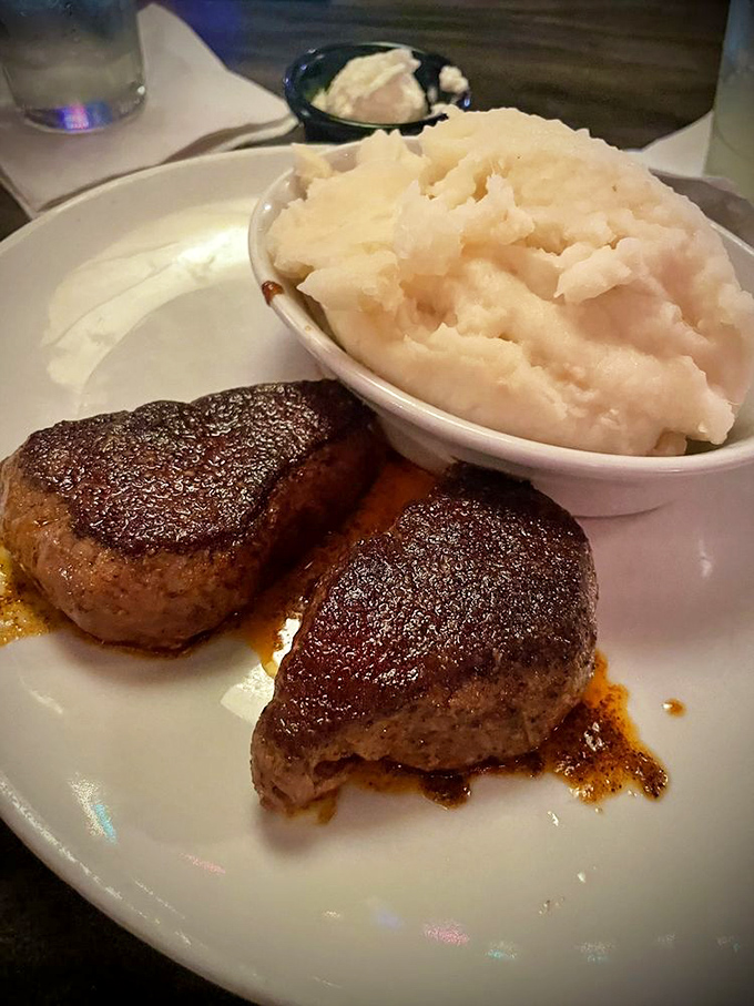 Two perfectly seared medallions of filet mignon alongside cloud-like mashed potatoes—a plate that whispers "special occasion" but tastes like "why don't we come here every week?"
